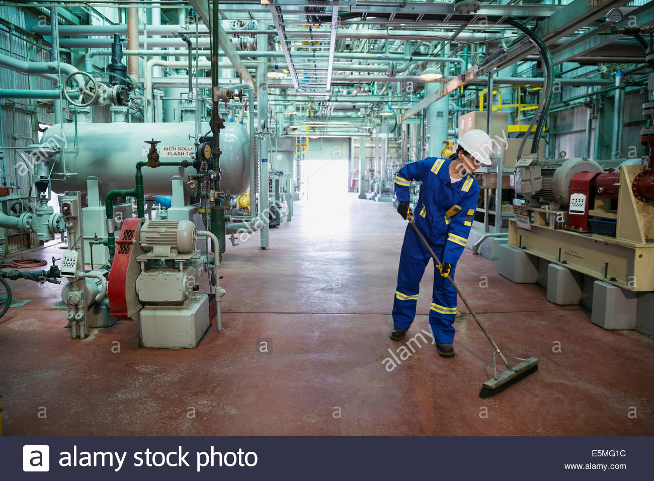 Female worker sweeping floor of gas plant Stock Photo - Alamy