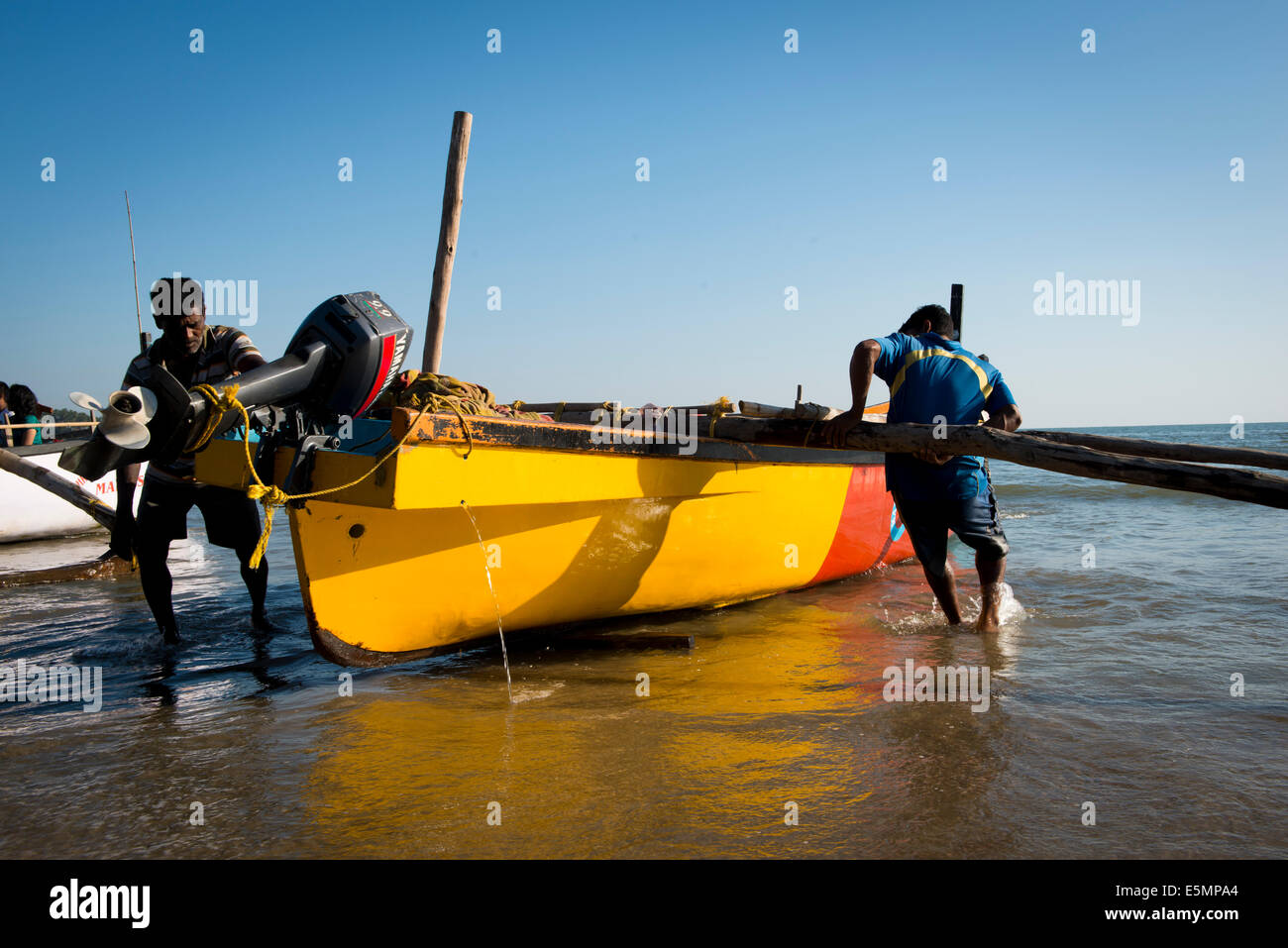 Fishermen haul their boat out of the water back onto the beach. Palolem ...