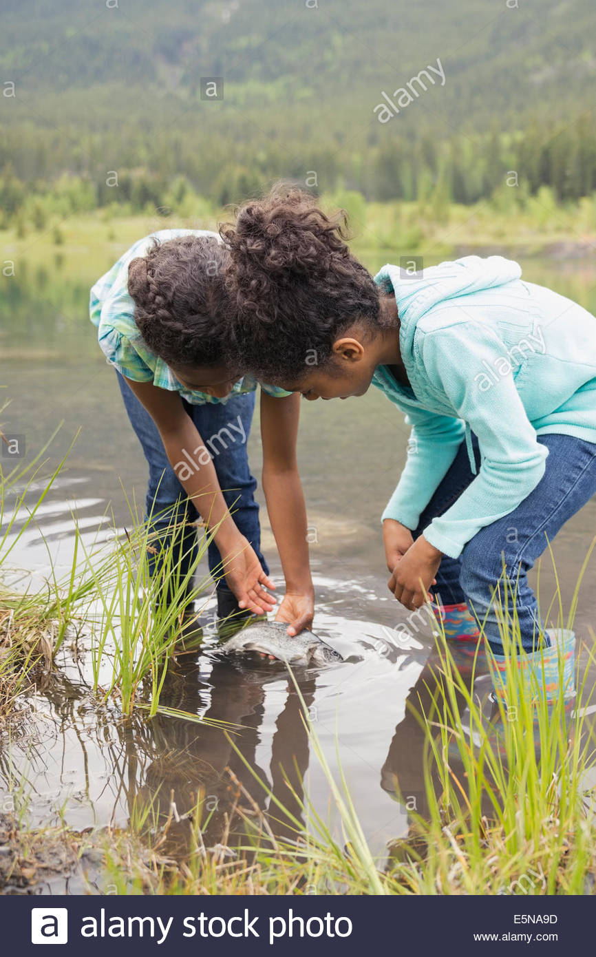 Girls catching fish in lake Stock Photo - Alamy
