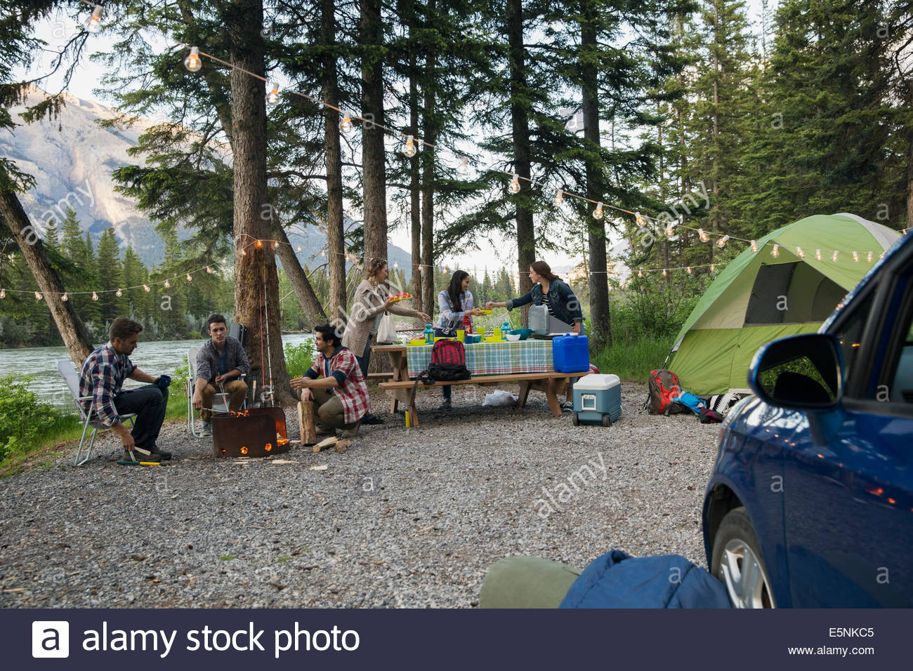 Friends at campfire at picnic table at campsite Stock Photo - Alamy
