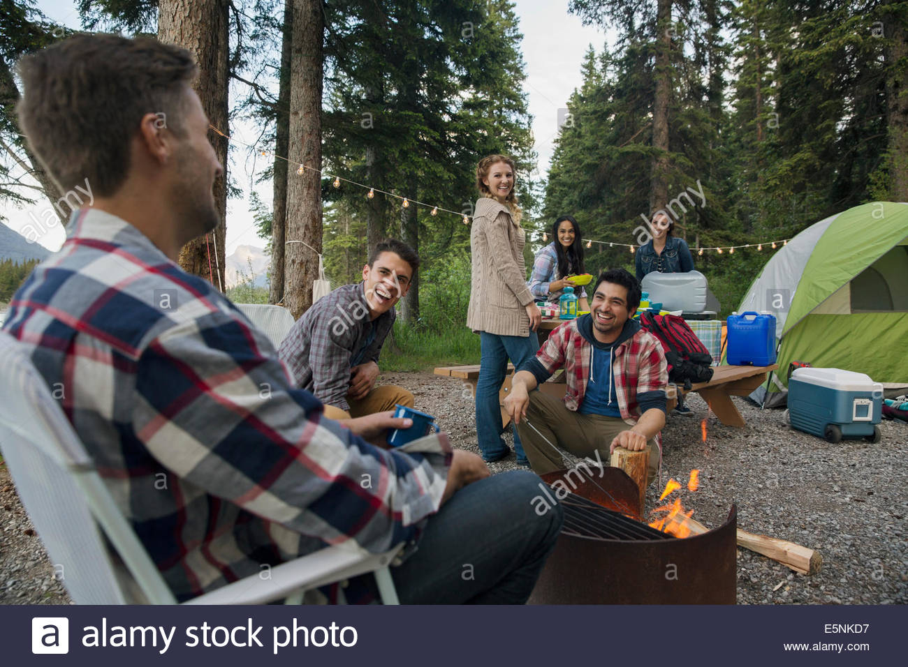 Friends hanging out around campfire at campsite Stock Photo - Alamy