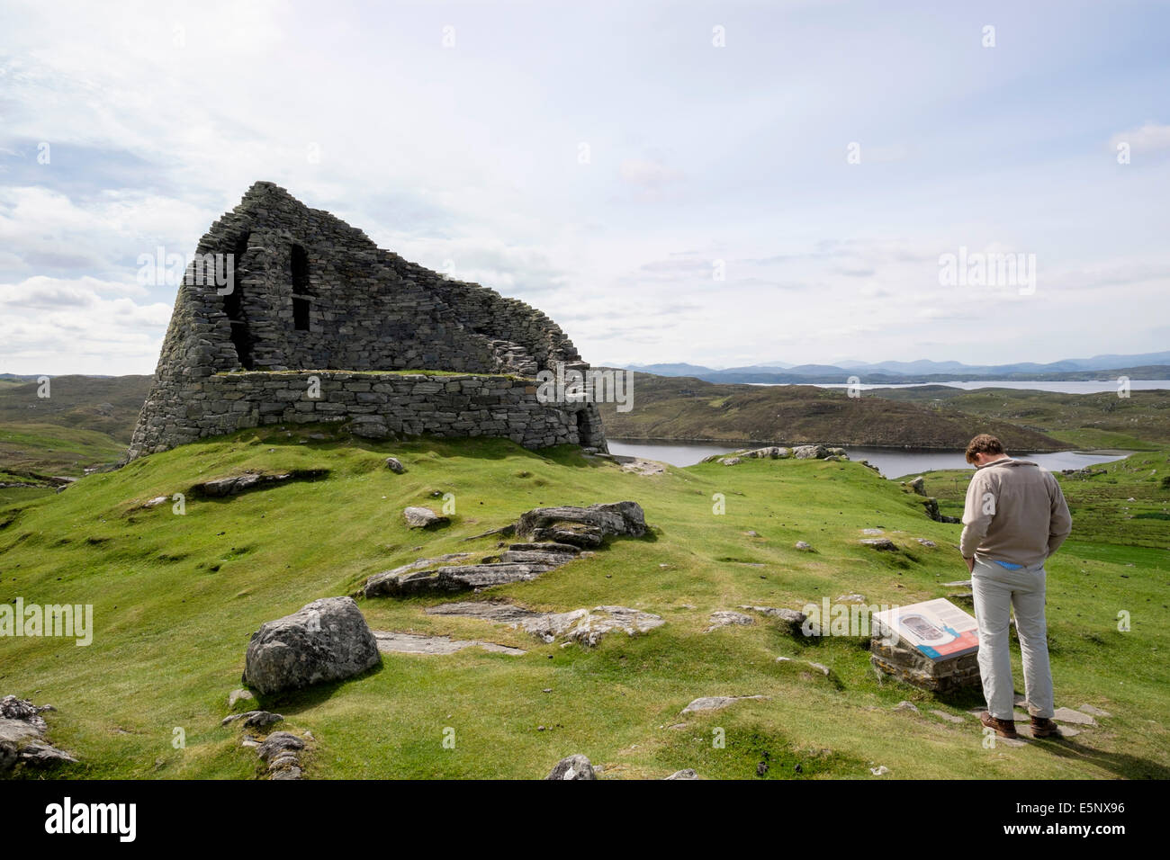 Tourist reading information board while visiting Dun Carloway Broch ...