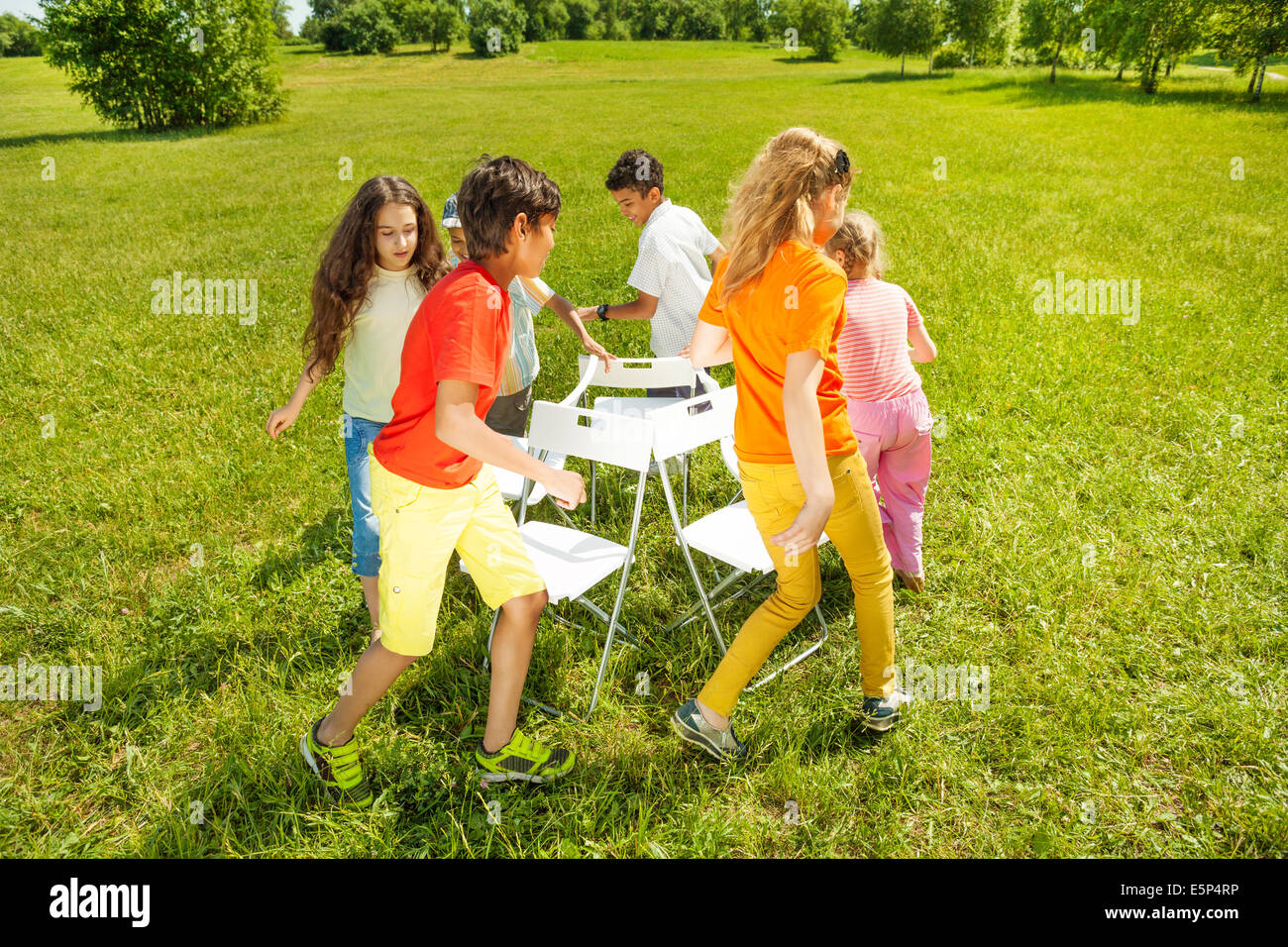 Kids run around playing musical chairs game Stock Photo - Alamy