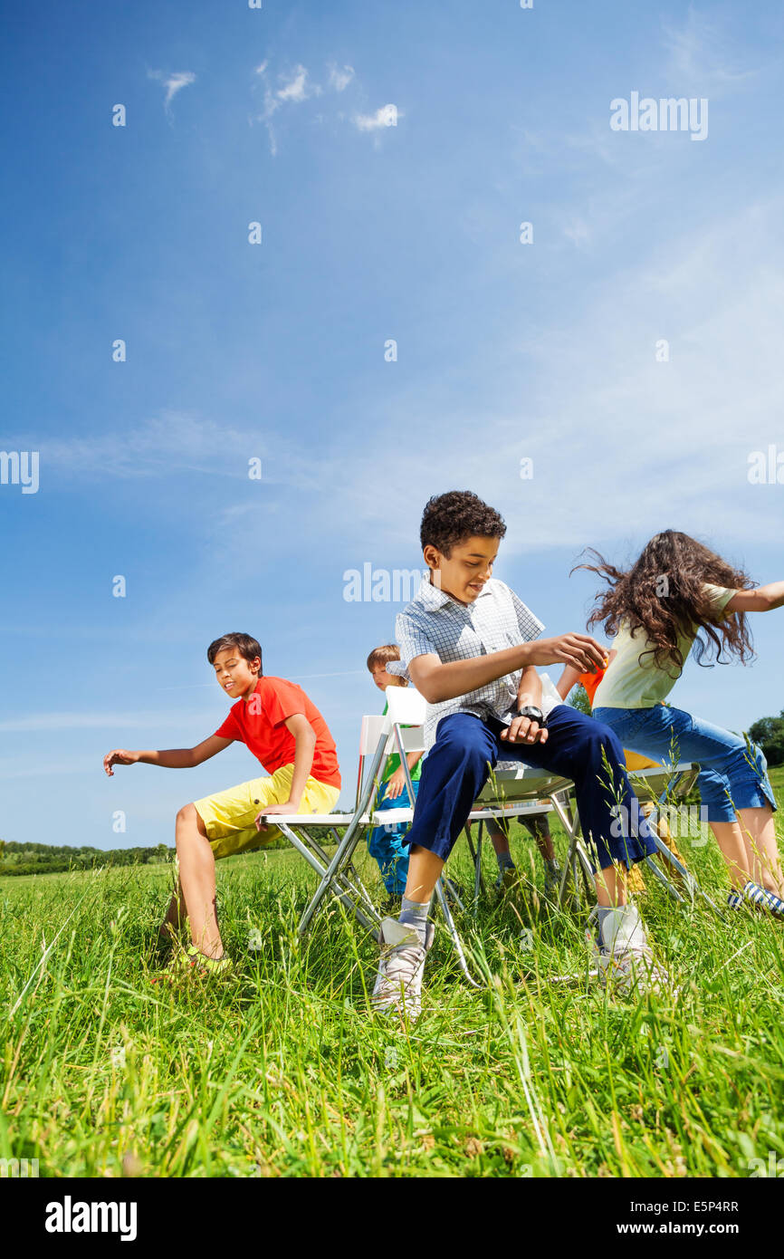 Kids playing game and sit fast on chairs outside Stock Photo - Alamy