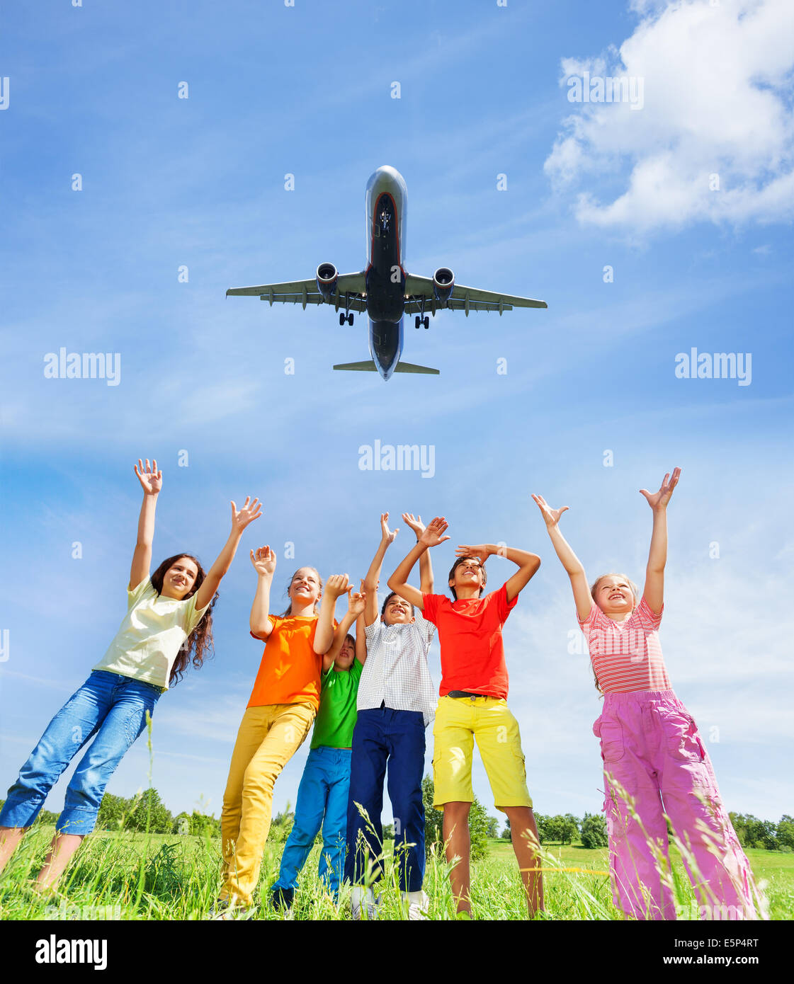 Excited children with hands up to plane in sky Stock Photo - Alamy