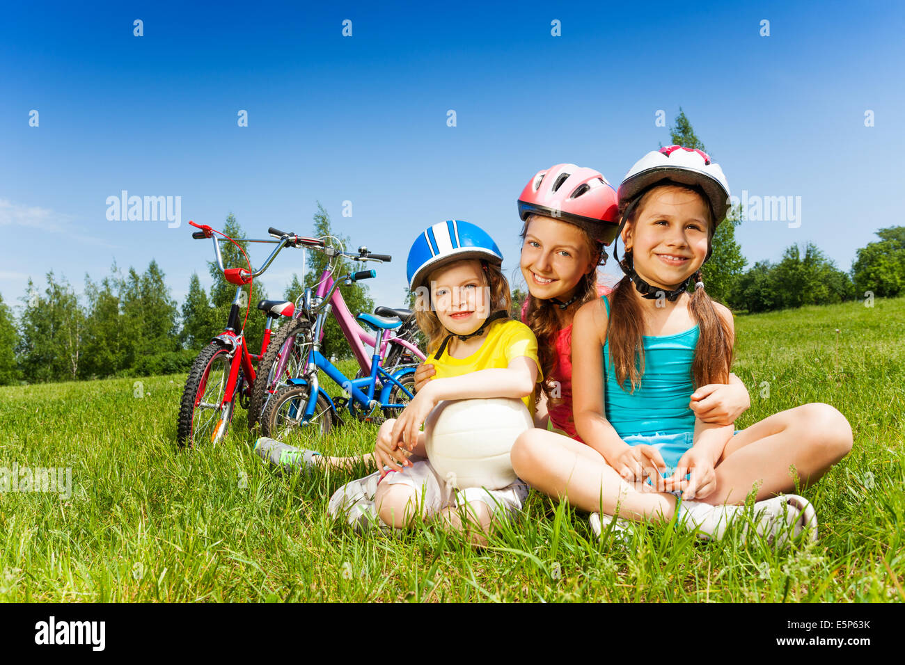 Three little girls sitting on a meadow Stock Photo - Alamy