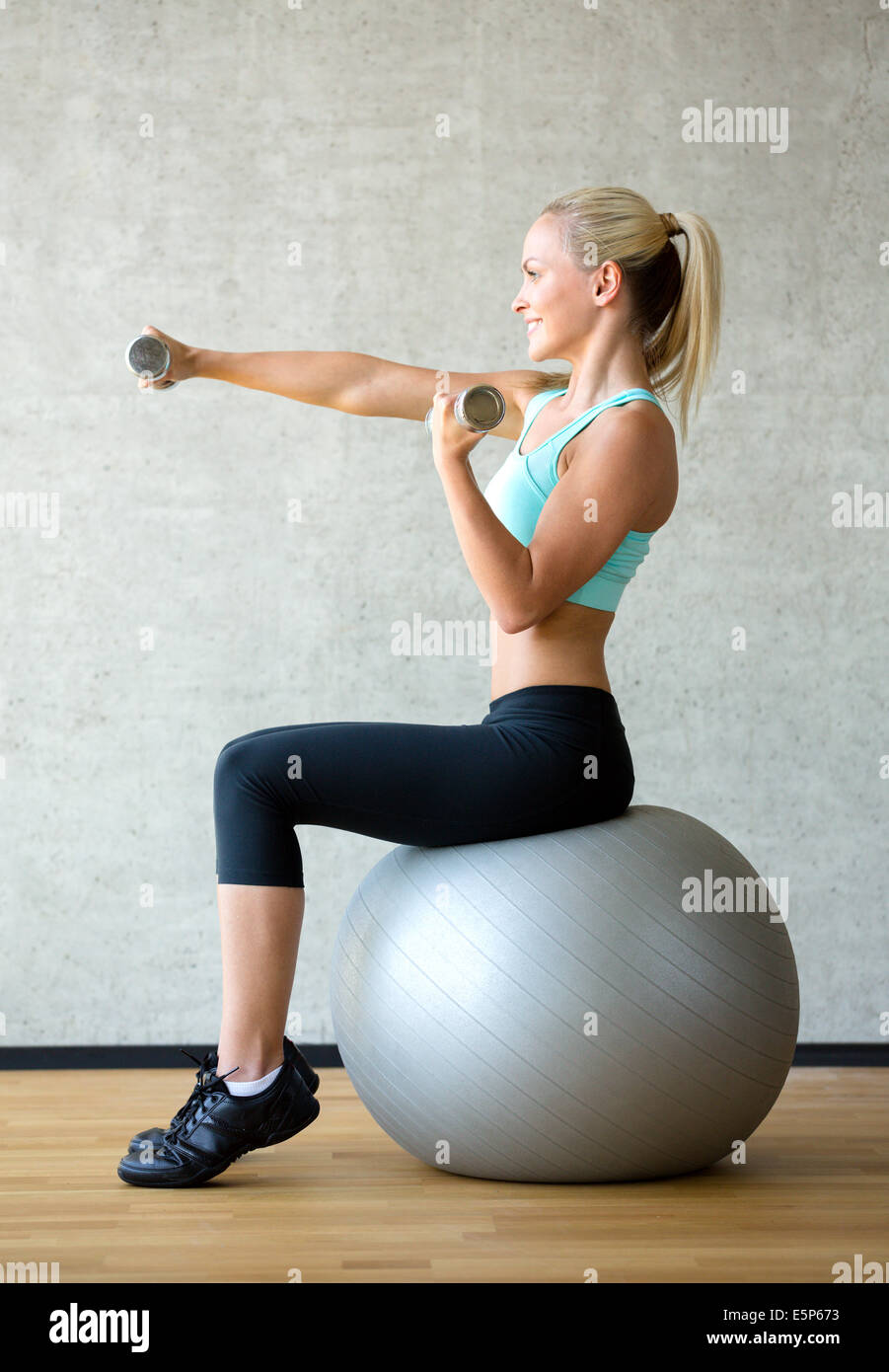 smiling woman with dumbbells and exercise ball Stock Photo - Alamy