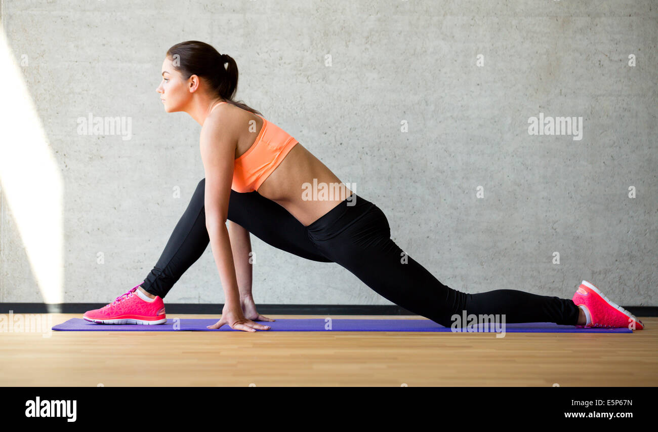 smiling woman stretching leg on mat in gym Stock Photo - Alamy