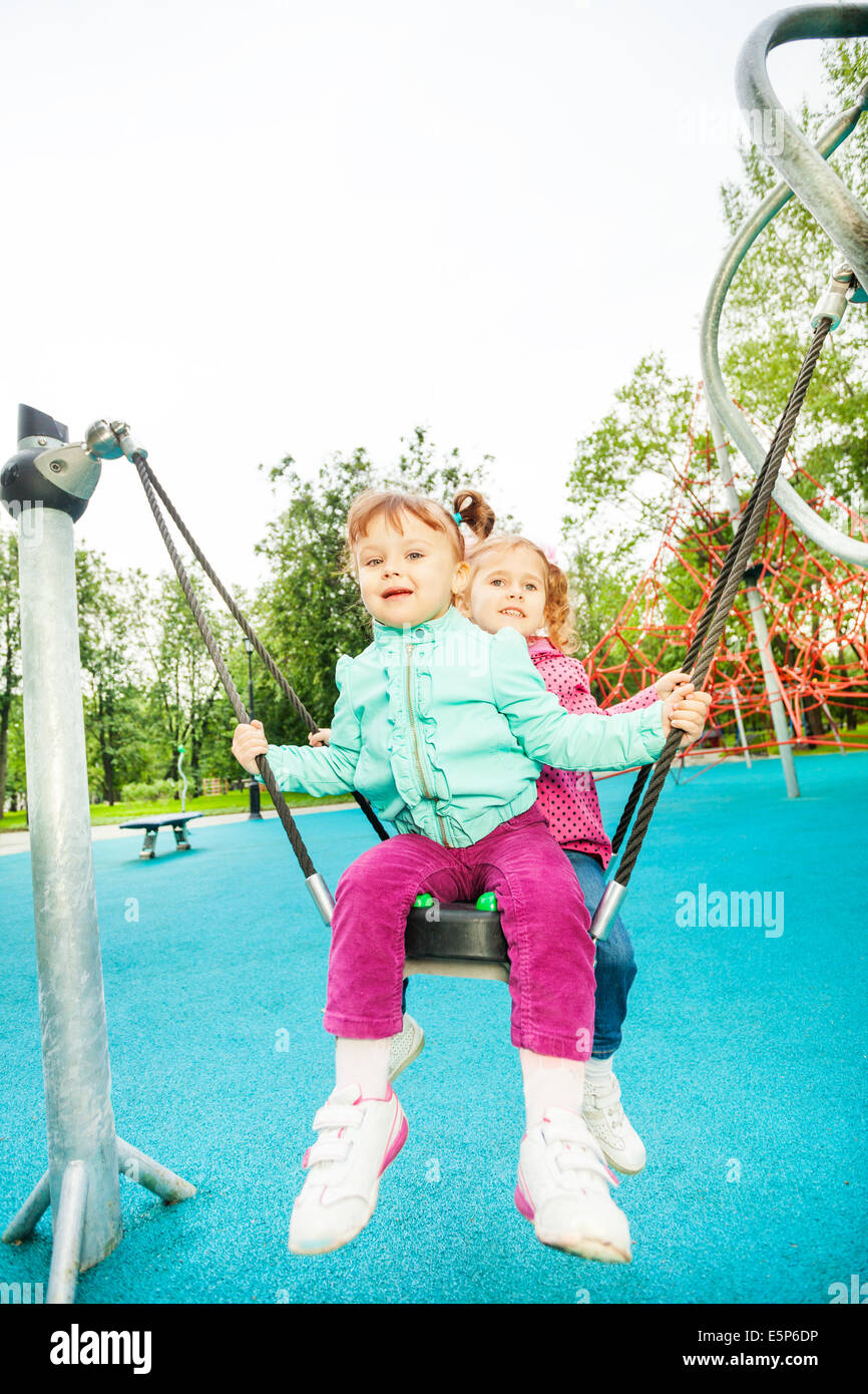 Two friends on swing set of playground Stock Photo - Alamy