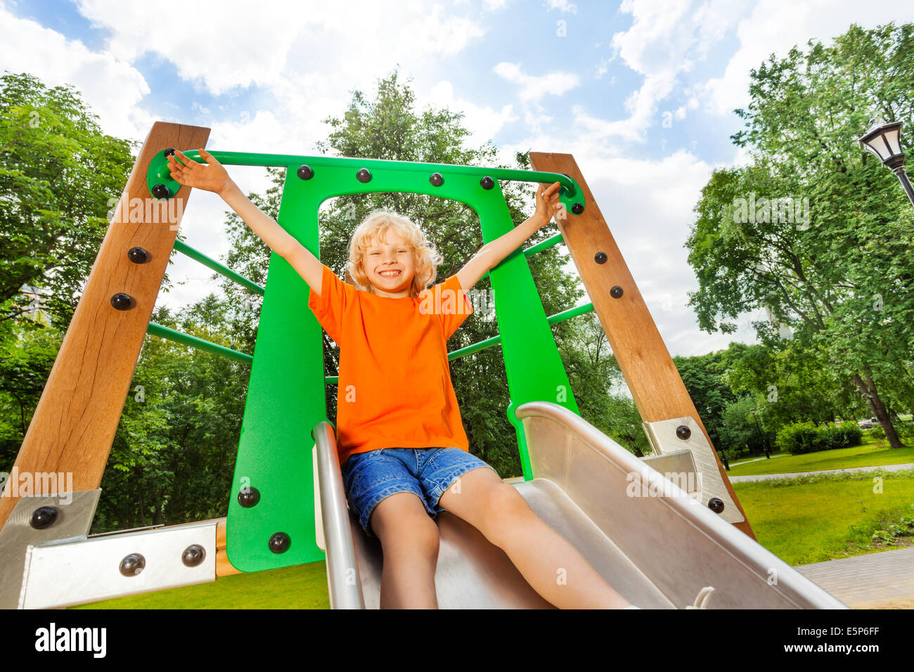Boy slides on playground chute with hands up Stock Photo - Alamy