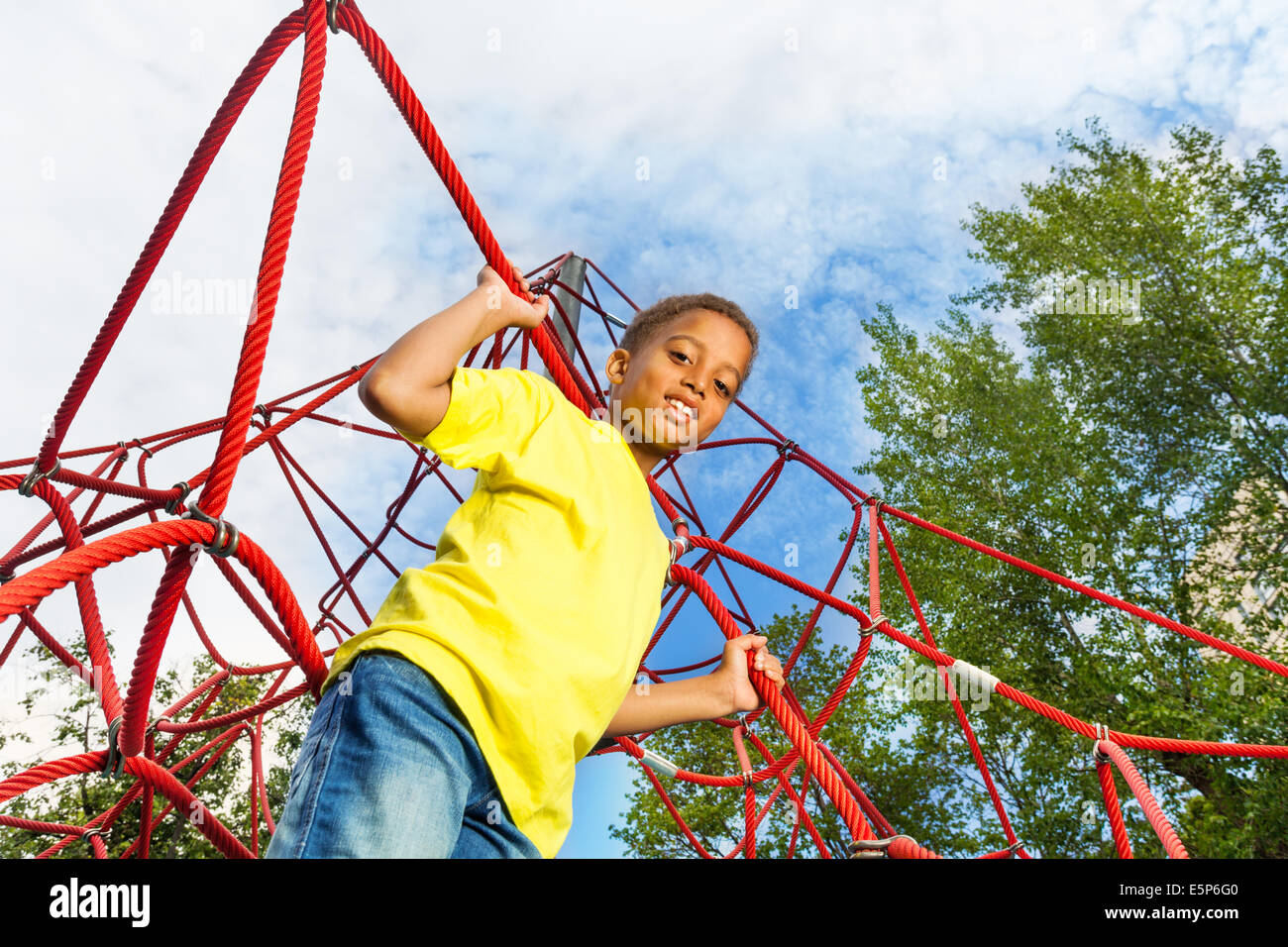 Funny boy holds and stands on red ropes Stock Photo - Alamy