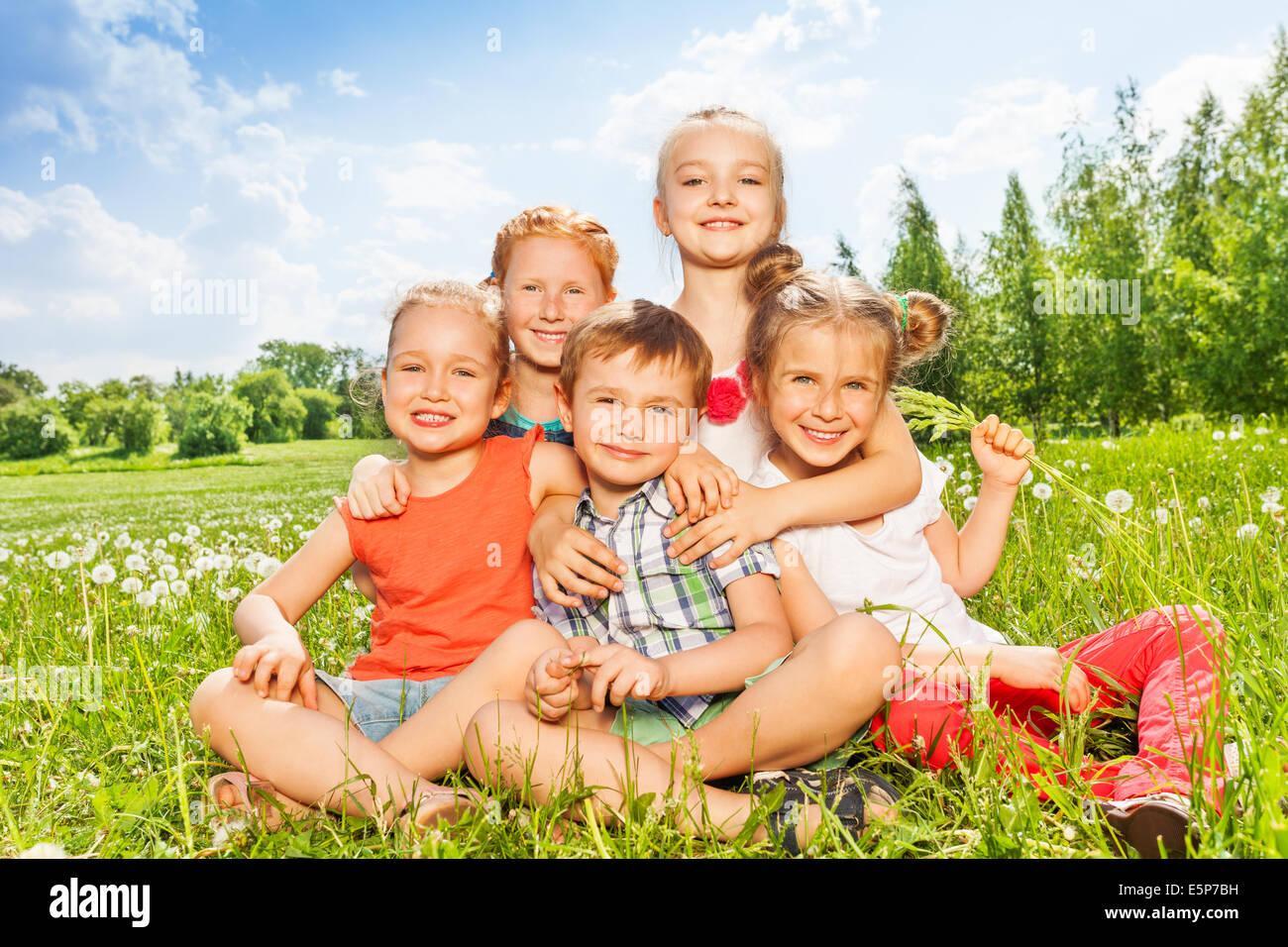 Five wonderful kids sitting together on a meadow Stock Photo - Alamy