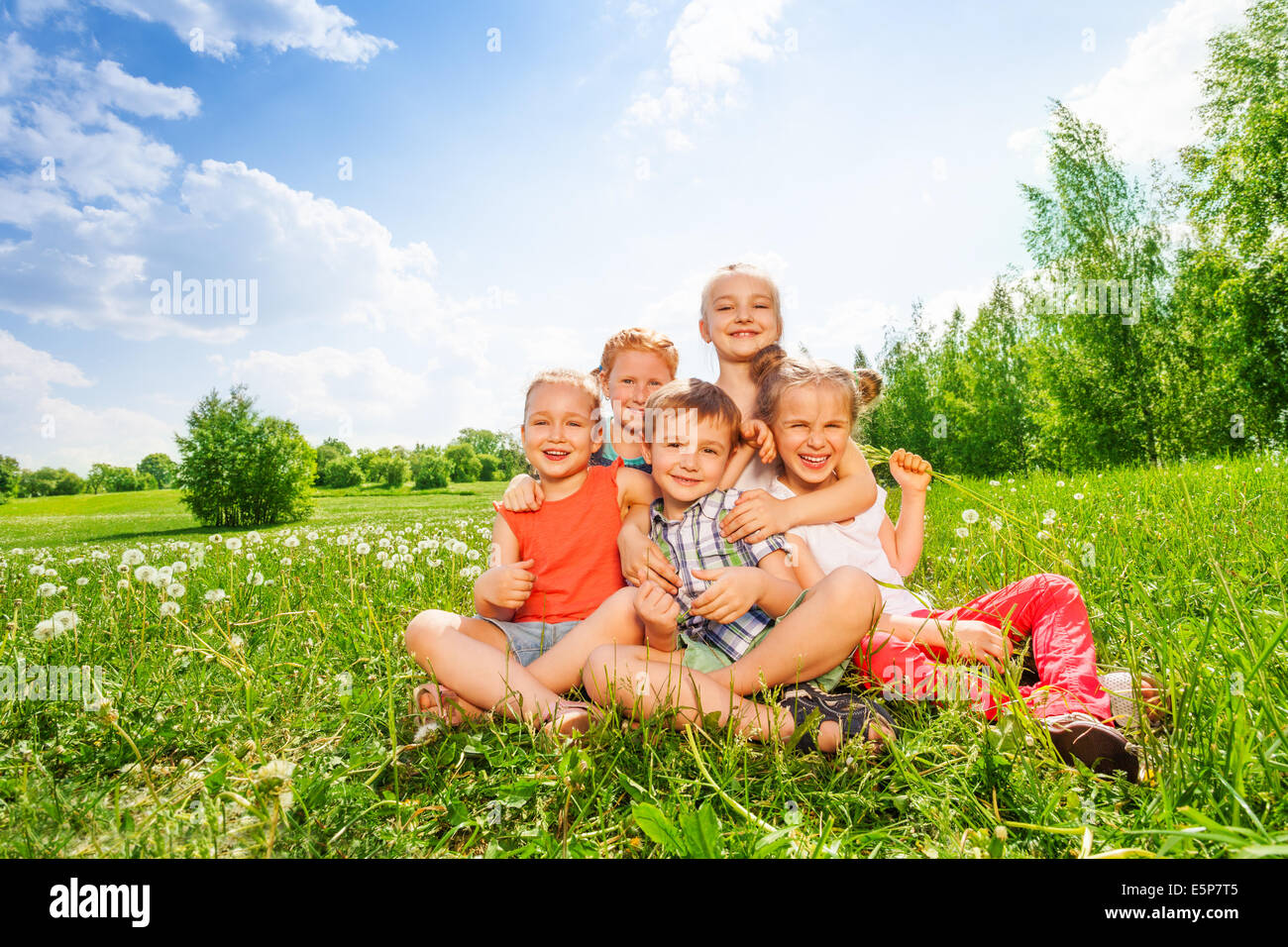 Five children sit together on a meadow Stock Photo - Alamy