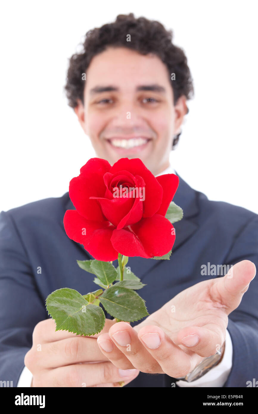 man in a suit holding a red rose and offers it to the camera to someone ...