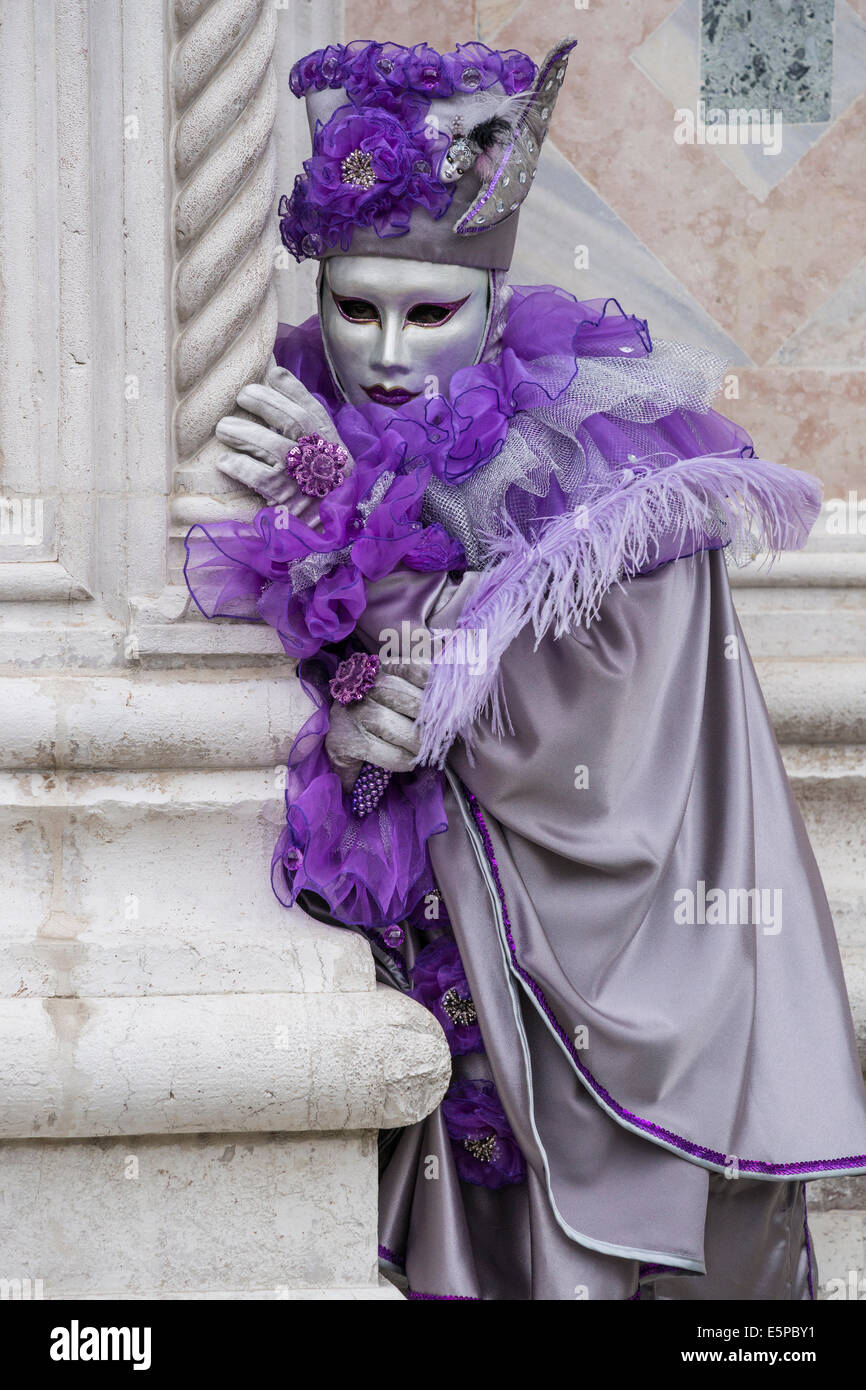Man in stylized sliver & purple clown costume looks out from column of ...