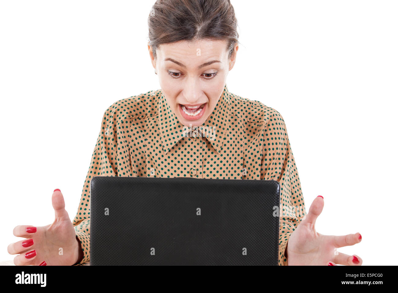 portrait of shocked young woman in shirt sitting and using laptop with ...