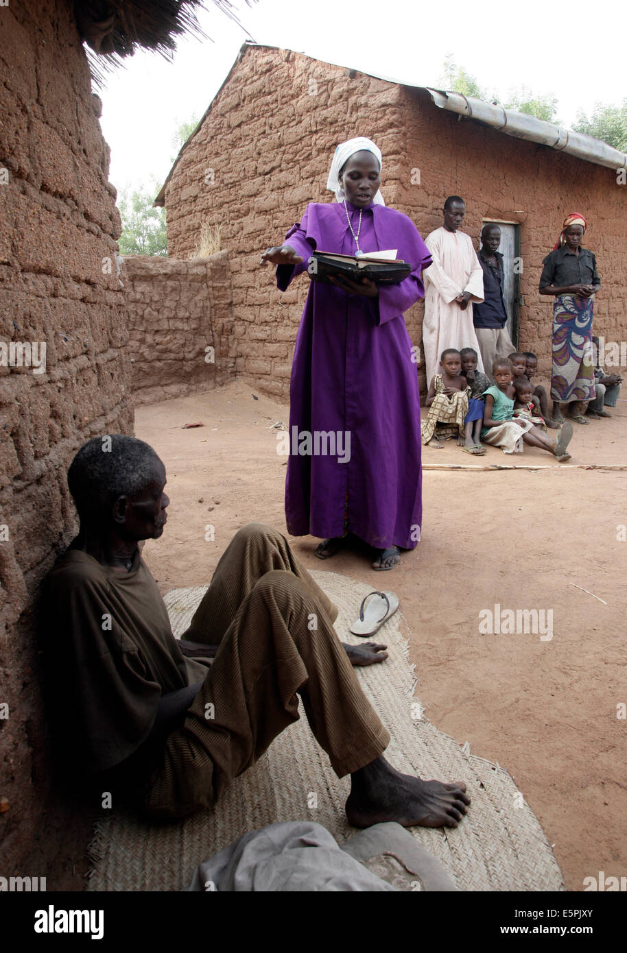 female catholic catechist praying and blessing an old man, village near ...