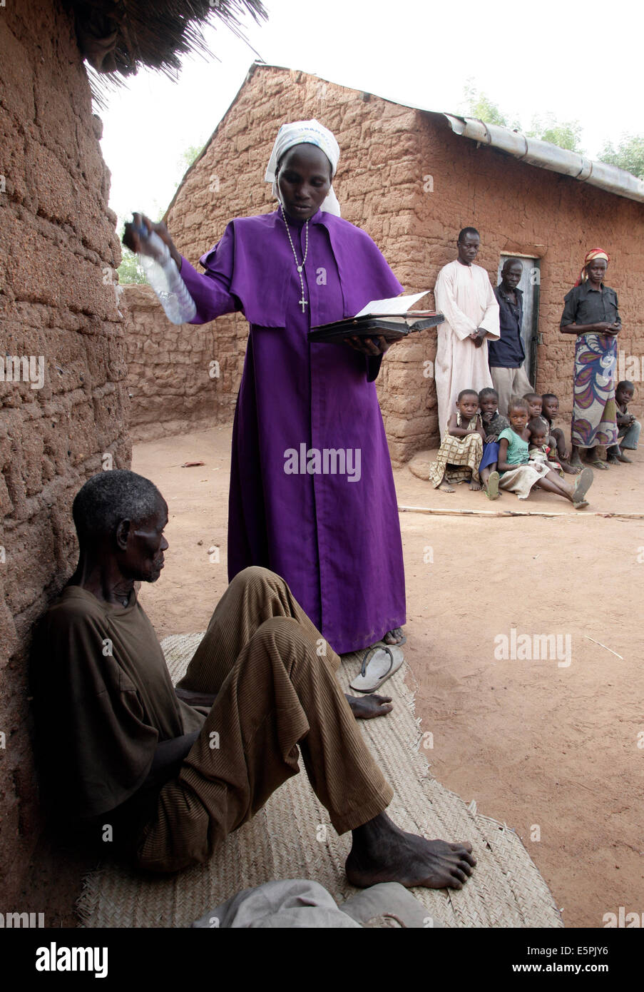 female catholic catechist praying and blessing an old man, village near ...