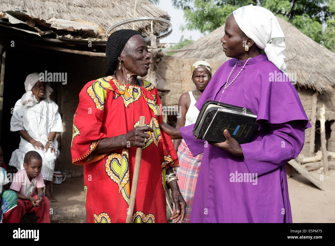 female catholic catechist (right) praying and blessing with people ...
