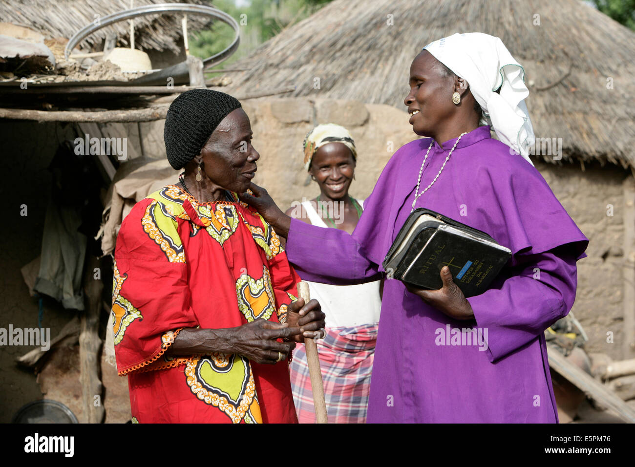 female catholic catechist (right) praying and blessing with people ...