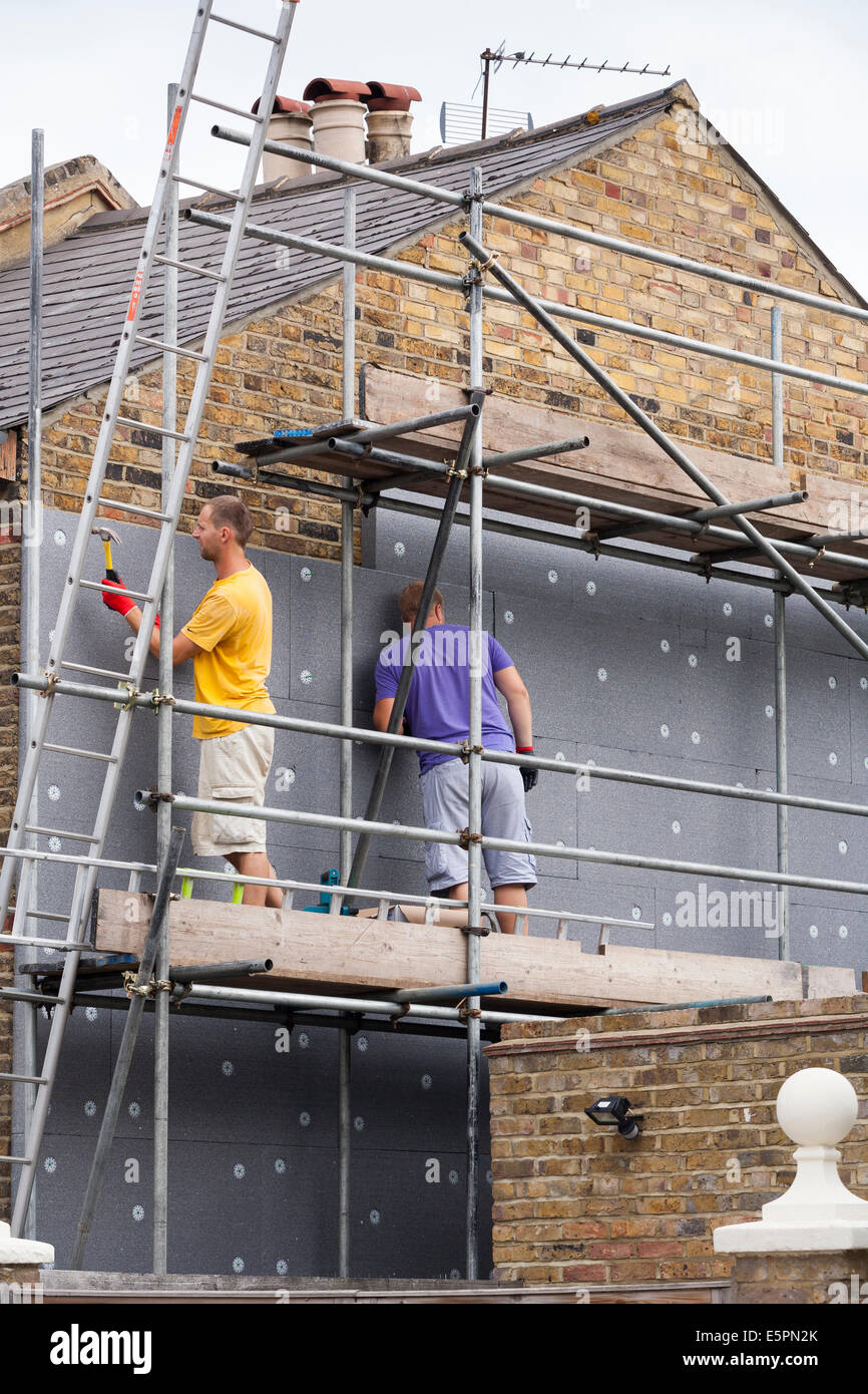 Builders attaching / fitting rigid foam wall insulation sheets / panels ...