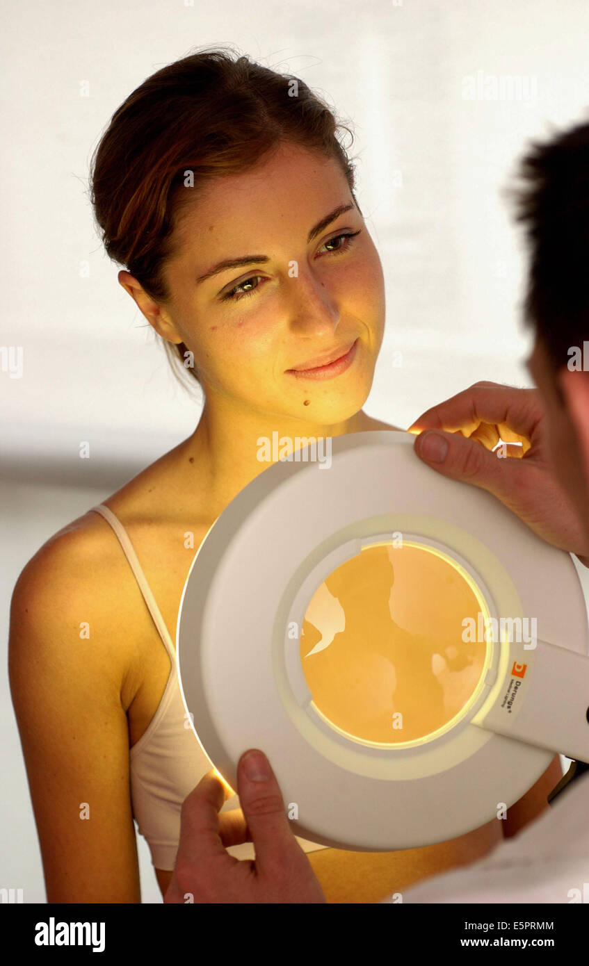 Dermatologist using a magnifying lens to examine the skin of a patient ...
