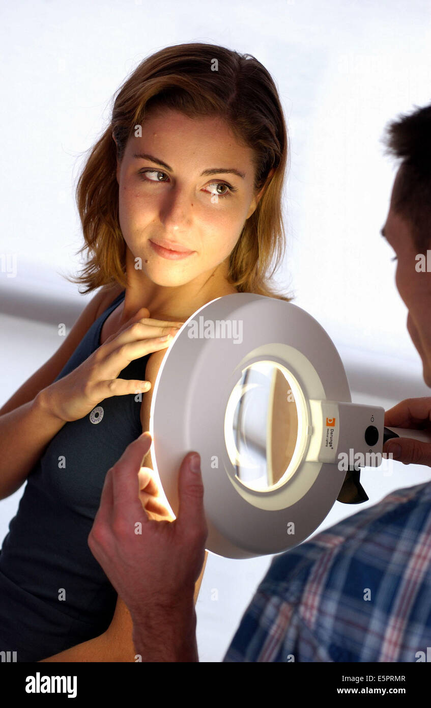 Dermatologist using a magnifying lens to examine the skin of a patient ...