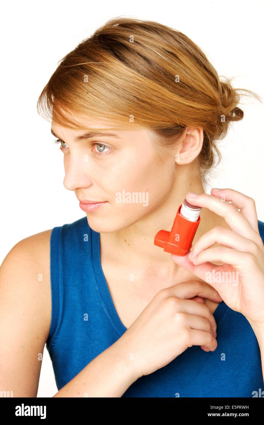 Woman using an aerosol inhaler that contains bronchodilator for the ...