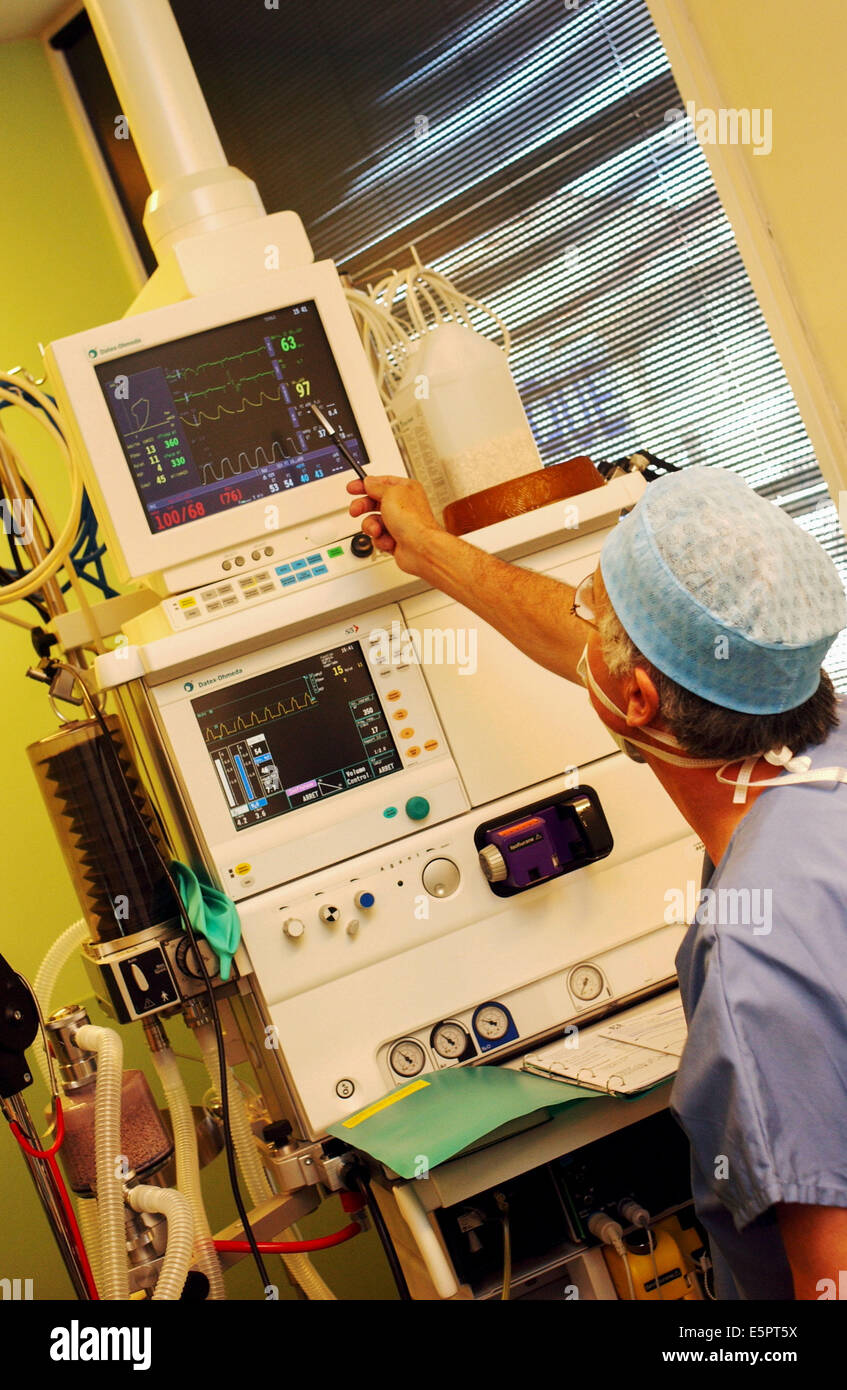 Anaesthetist in surgical dress beside anaesthetic monitoring equipment ...