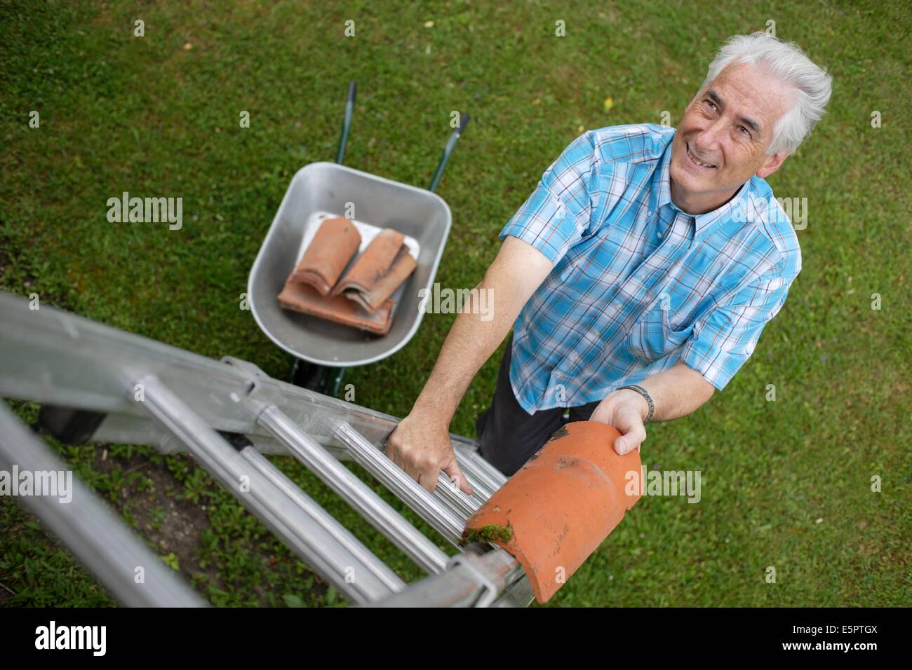 Senior man doing maintenance work of his roof with a ladder Stock Photo ...
