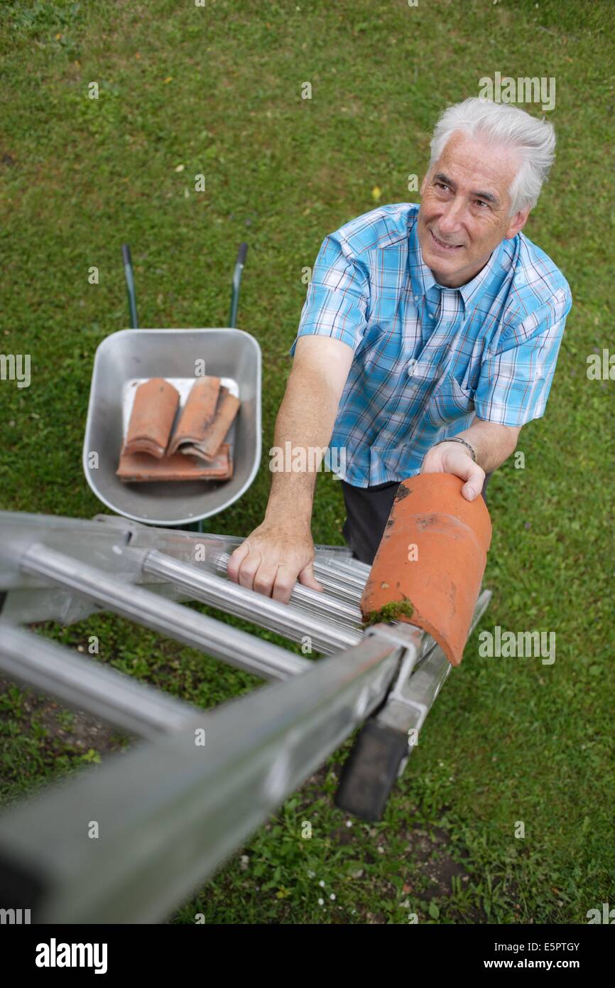 Senior man doing maintenance work of his roof with a ladder Stock Photo ...