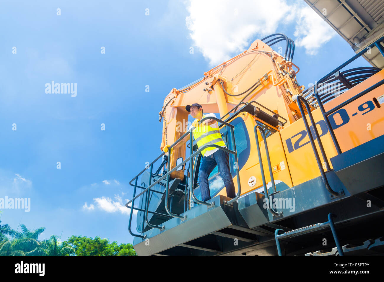 Asian driver standing on construction machinery on building site Stock ...