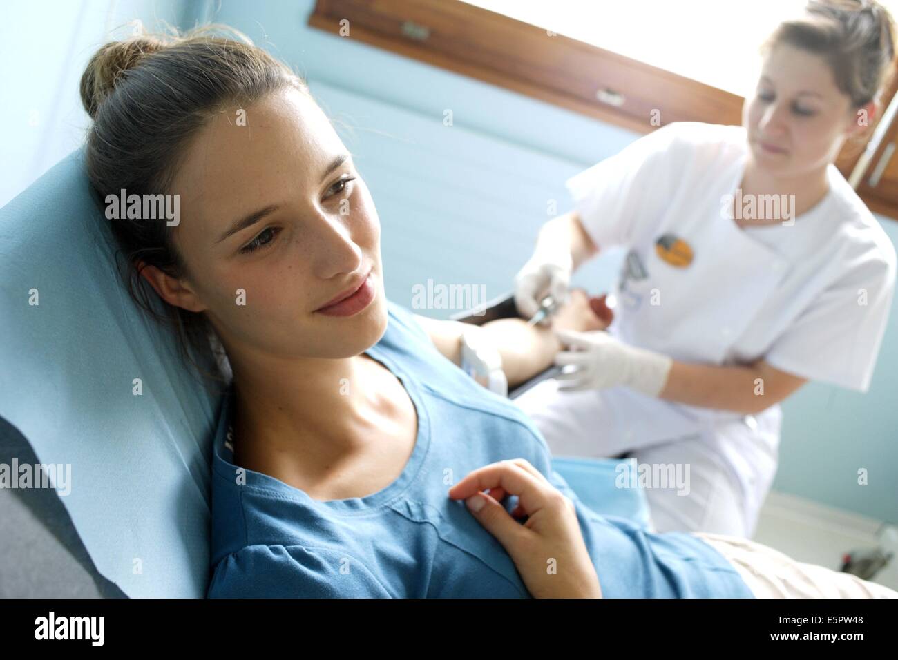 Nurse injecting a solution of radioactive isotopes to a female patient ...