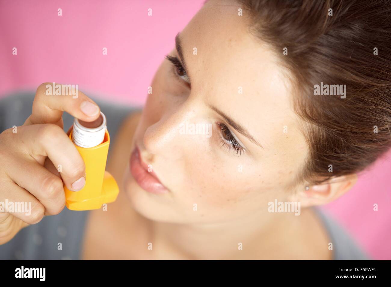 Woman using an aerosol inhaler that contains bronchodilator for the ...