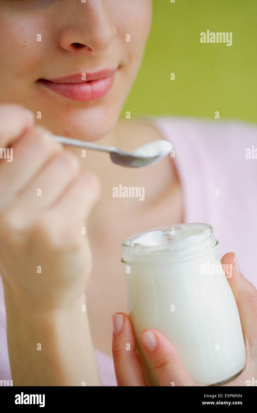 Woman eating a yogurt Stock Photo - Alamy