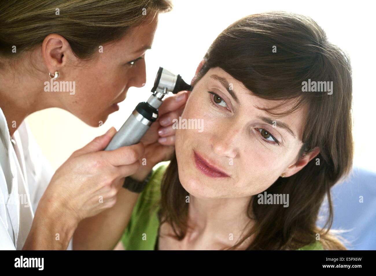 Female doctor examining ears of a female patient with an otoscope Stock ...