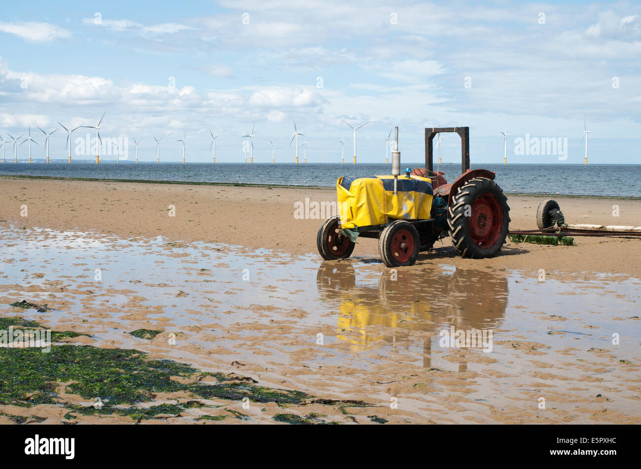 A tractor, used to launch fishing boats, on Redcar beach with offshore ...