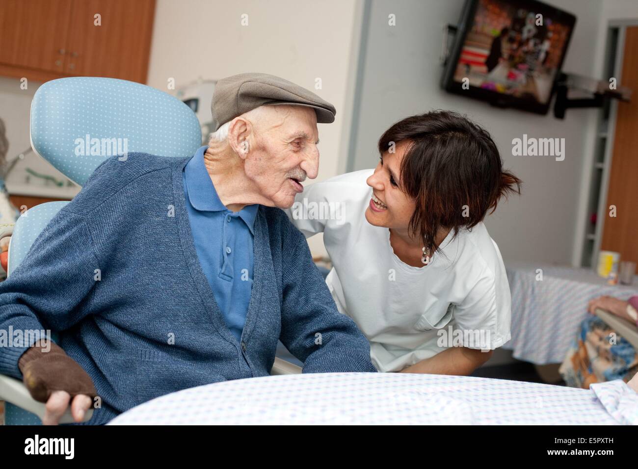 Auxiliary nurse talking with centenarian man; Residential home for ...