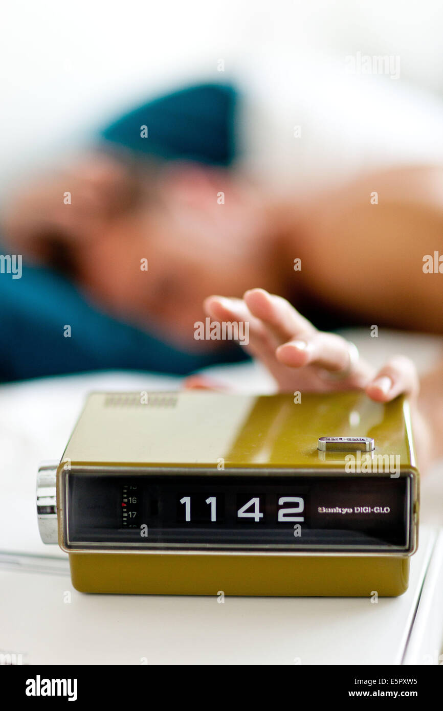 Man's hand on alarm clock Stock Photo - Alamy