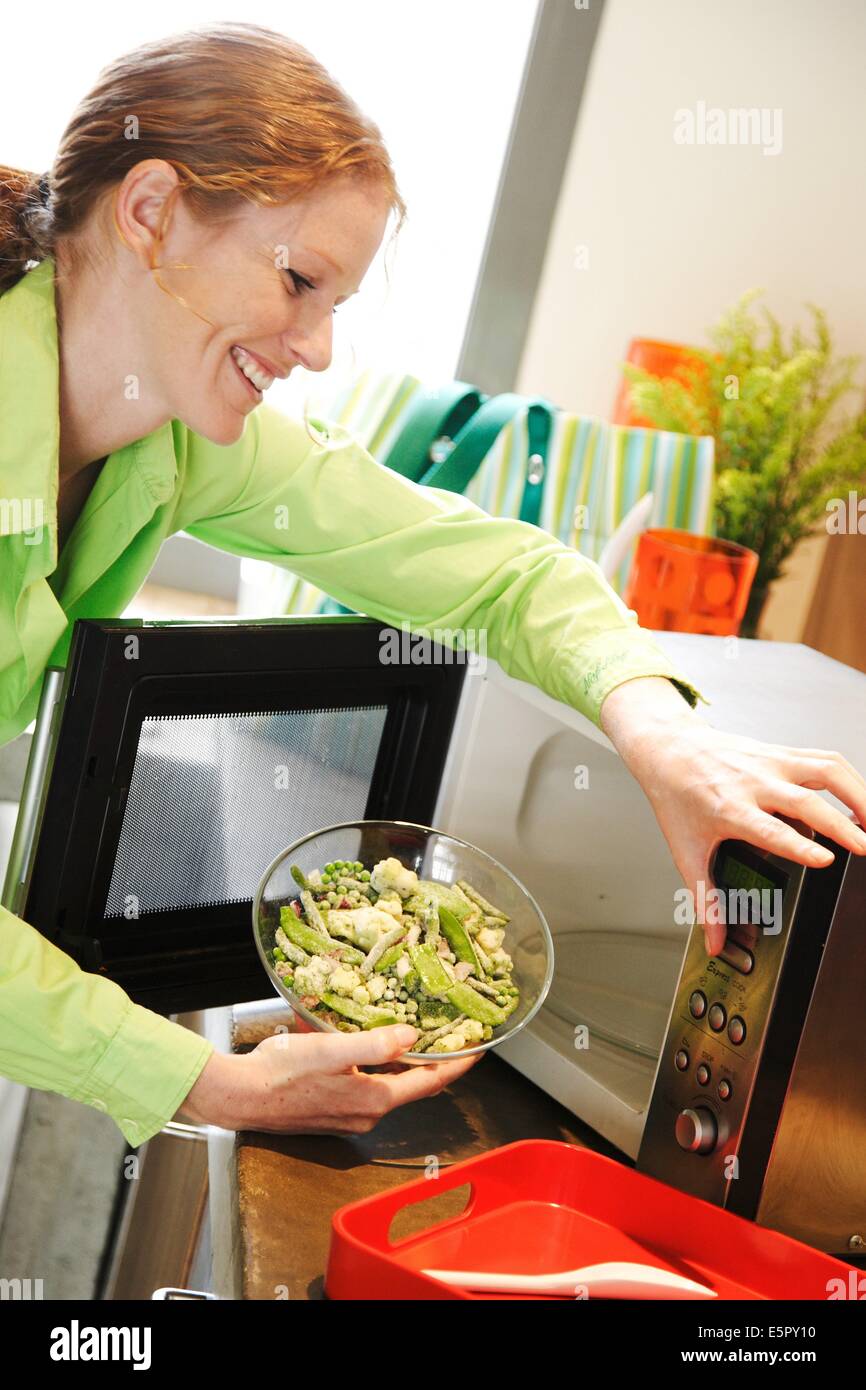 Woman using a microwave oven Stock Photo - Alamy