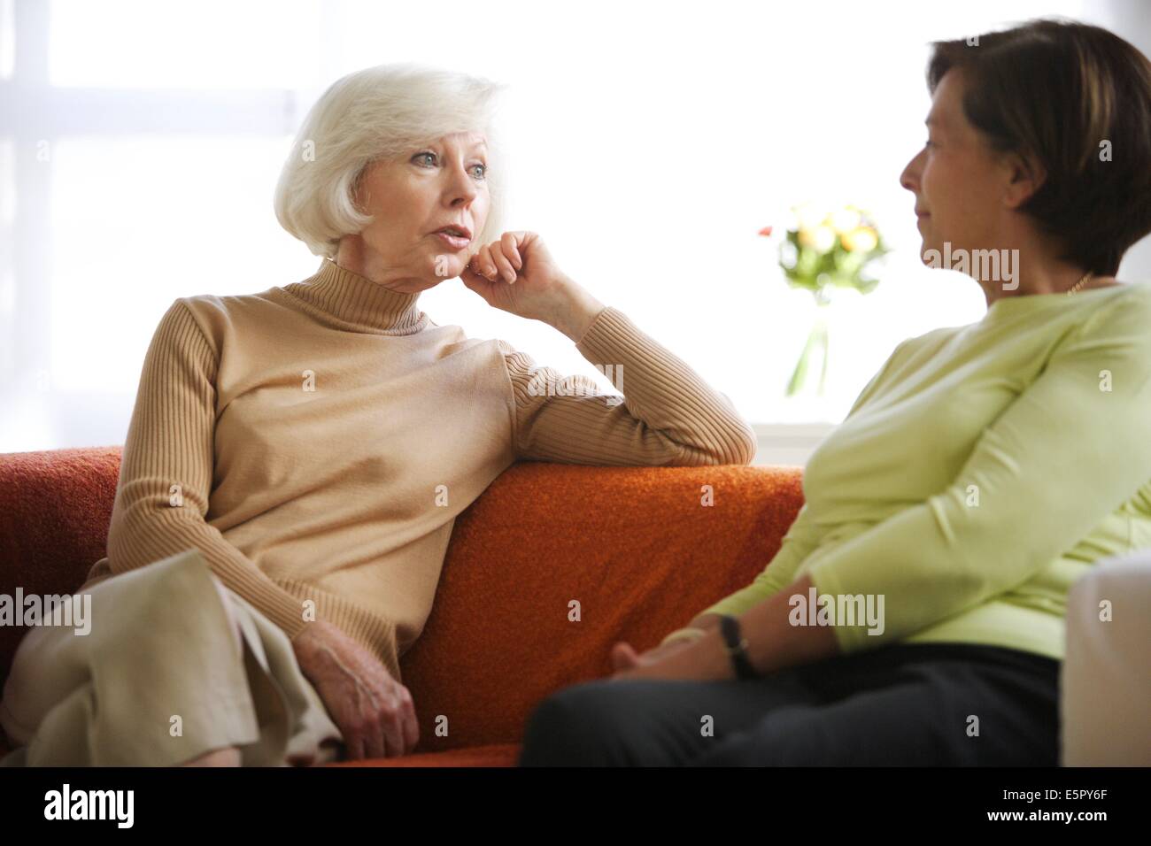 Woman and elderly woman talking at home Stock Photo - Alamy