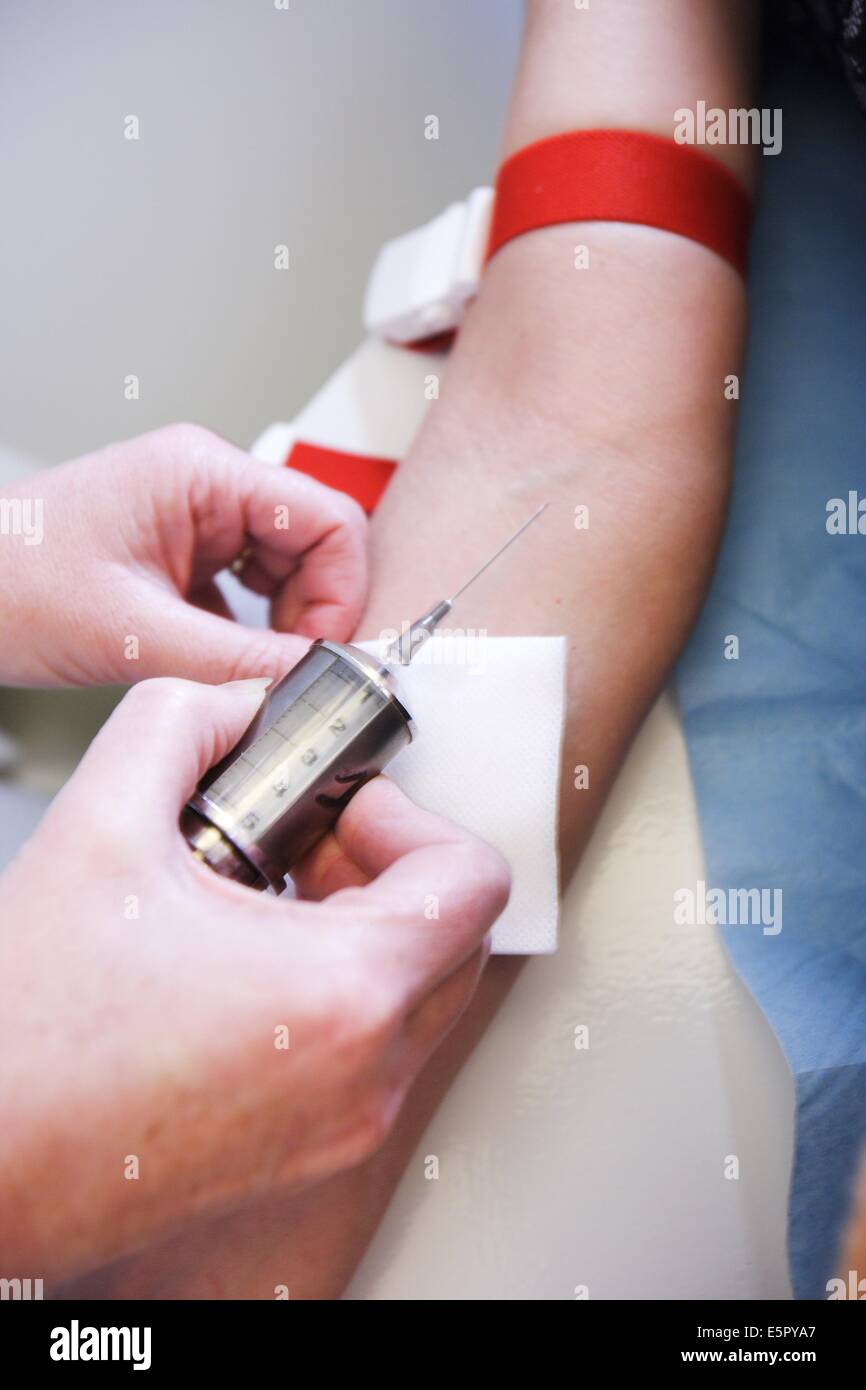 A nurse is injecting a solution of radioactive isotopes to a patient ...