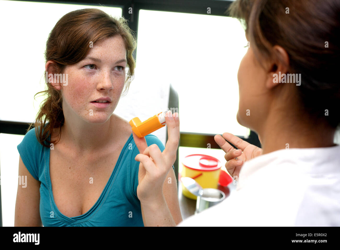 A doctor explains a female teenager the use of a spray bronchodilatator ...