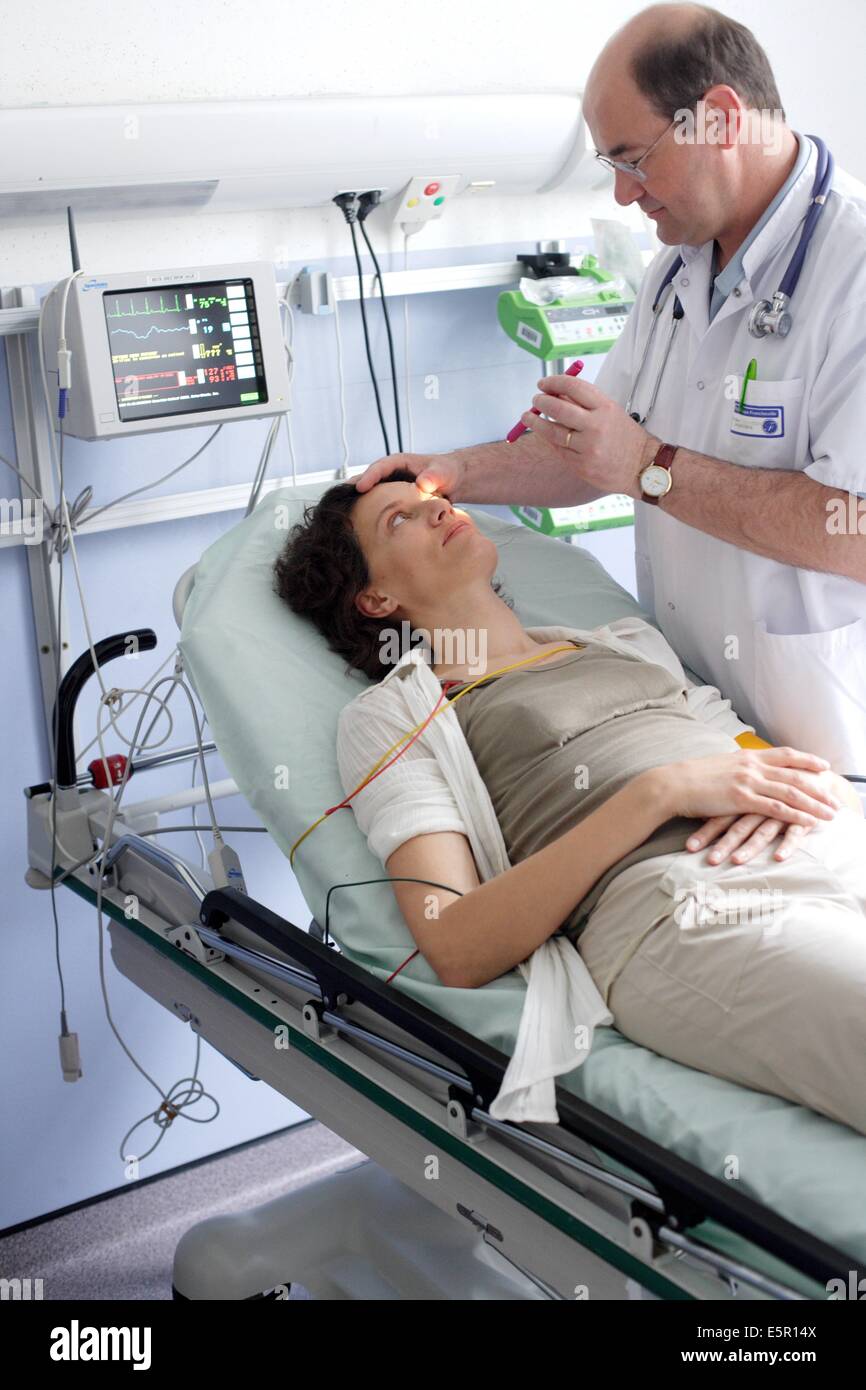 Assessing pupil dilation : hospital doctor performing neurological ...