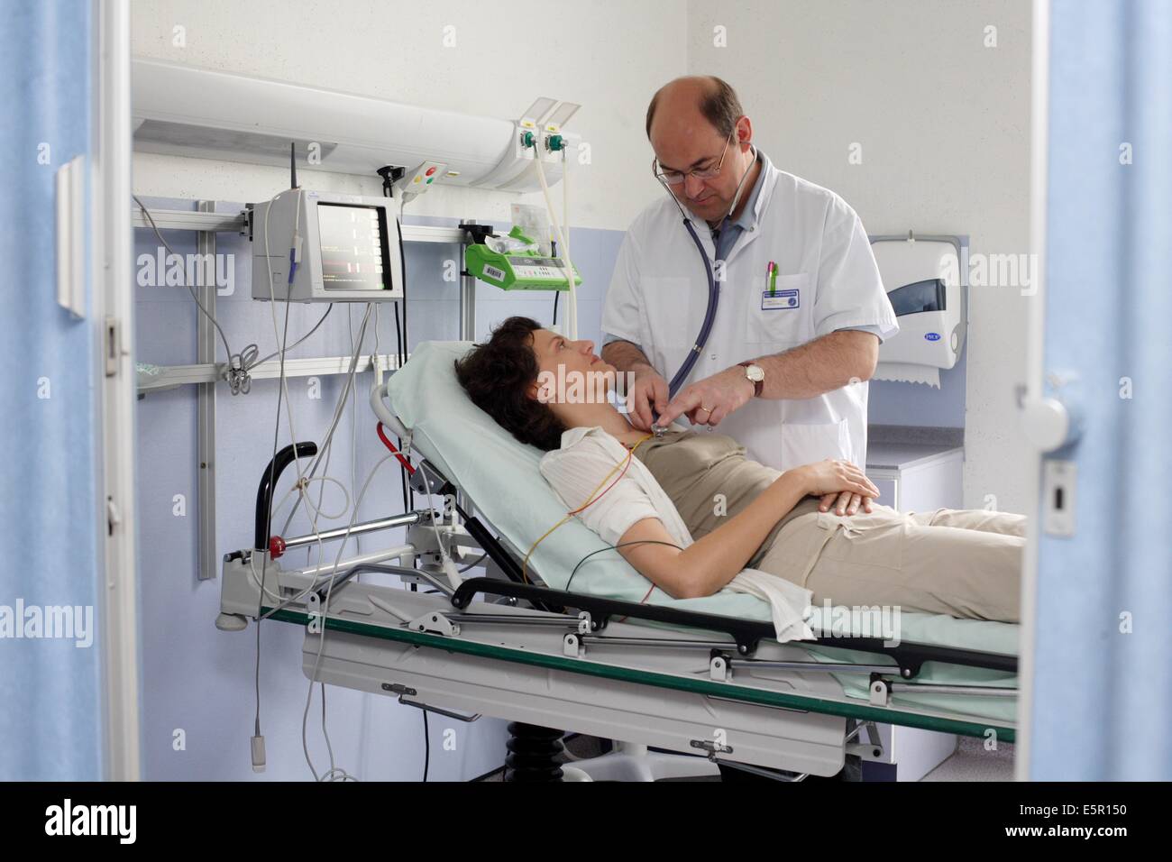 Hospital doctor examining a patient with a stethoscope at emergency ...