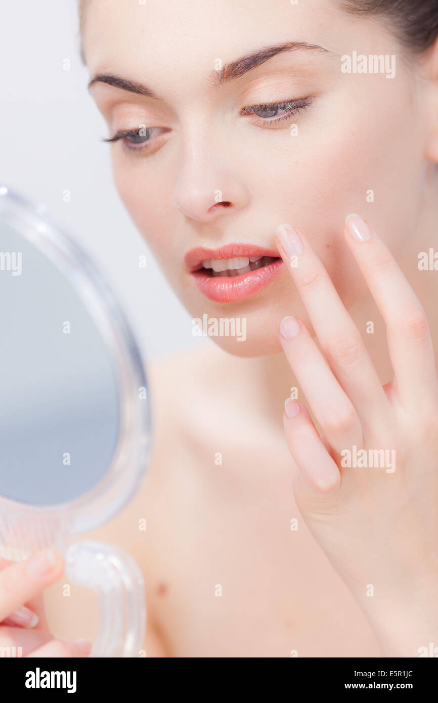 Woman checking her face in the mirror Stock Photo - Alamy