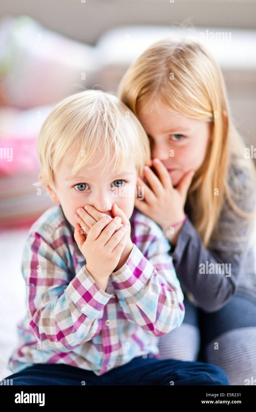 Girl whispering in brother's ear Stock Photo - Alamy
