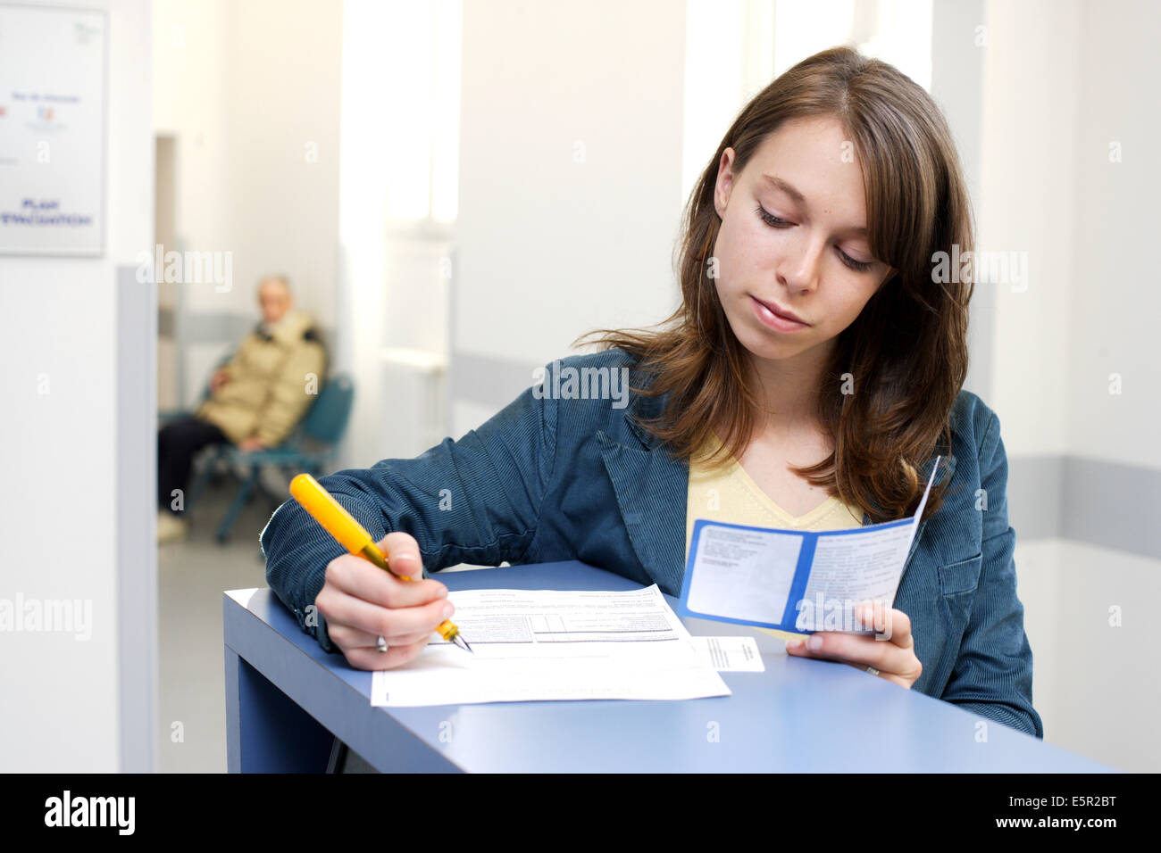 Woman filling form at reception desk Stock Photo - Alamy
