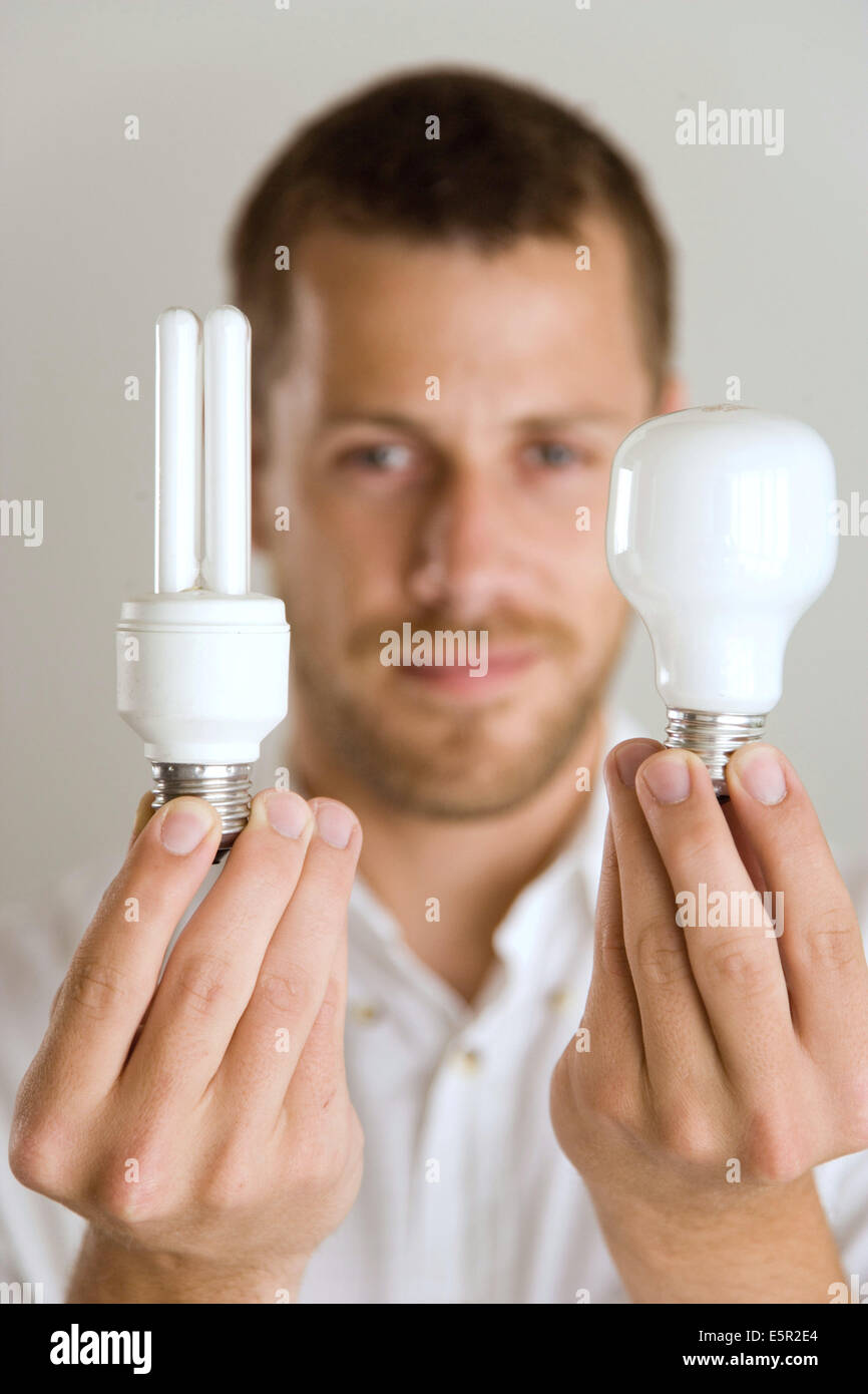 Man holding a low energy bulb at left and a regular bulb at right Stock ...