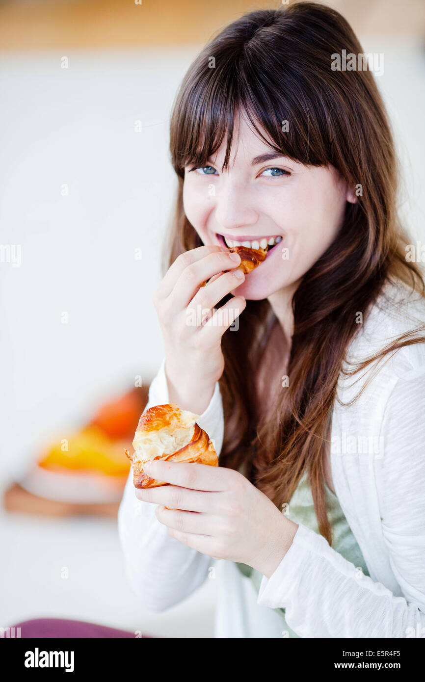 Woman eating croissant Stock Photo - Alamy